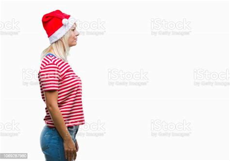 사이드로 보고 격리 된 배경 위에 젊은 아름 다운 금발의 여 자가 입고 크리스마스 모자 긴장 자신감 미소와 자연 스러운 얼굴