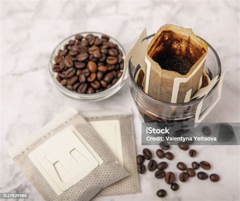 집에서 커피를 만드는 추세 갈색 배경에 커피 원두가 든 유리잔에 신선한 음료가 담긴 가방을 드립한다 컵에 양조하기위한 분쇄 커피