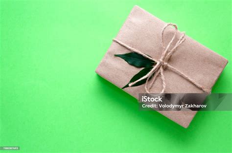 줄이 달린 크래프트 종이에 싸여 있고 밝은 녹색 배경에 두 개의 녹색 잎으로 장식 된 선물 상자 제로 폐기물 휴일 개념 Diy 선물 아이디어 공간을 복사합니다 플랫 레이