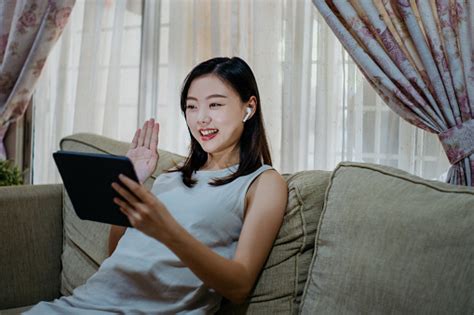 젊은 아시아 여자 는 거실에서 디지털 태블릿과 화상 통화를 무선 인이어 헤드폰에 대한 스톡 사진 및 기타 이미지 무선 인이어 헤드폰 30 34세 가정 생활 Istock