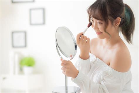 뷰티 초상화 젊은 아시아 여성은 침실에 브러시 뺨과 메이크업을 적용 얼굴을 찾고 거울 블러셔를 들고 여자의 아름다운 스킨 케어 및 화장품 개념으로 미소 가정 생활에 대한