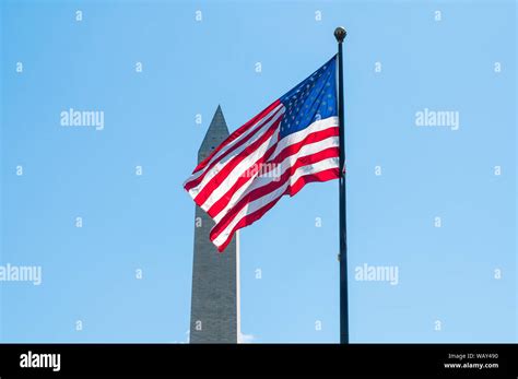 Us Flag Flying From A Pole With Washington Monument In Background Stock