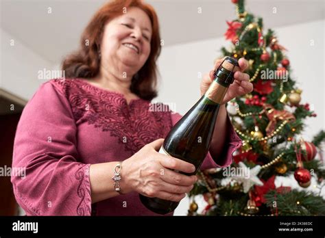Latin Mature Woman Smiling While Opening A Bottle Of Champagne Or Cider