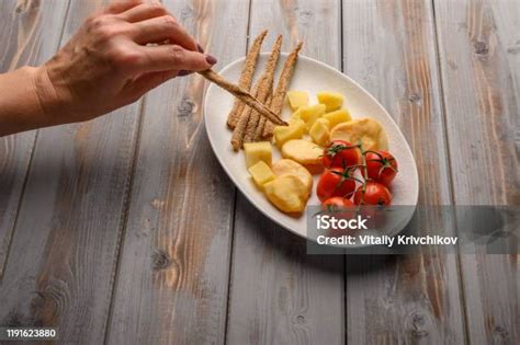 이탈리아 음식은 프로슈토 치즈 토마토를 곁들인 그리시니 빵입니다 여자의 손에는 빵 막대기가 붙어 있다 건강한 스타일 맨 위 보기