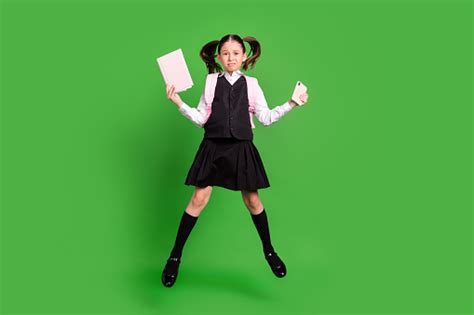 밝은 녹색 색상 배경을 통해 고립 된 책 장치를 들고 점프 꽤 트렌디 한 슬픈 소녀의 전체 길이 바디 사이즈 보기 점프에 대한