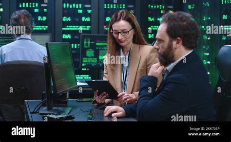 Two Programmers Work Together In Server Room At Desktop Woman Holds