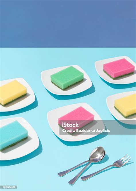 밝은 파란색과 보라색 배경에 포크와 숟가락이 있는 흰색 접시에 다채로운 주방 청소 스폰지로 만든 창의적인 구성 트렌디한 설거지 개념 아트 디렉션 가사 집안일에 대한 스톡