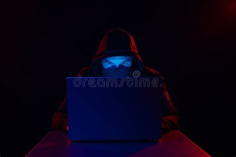 Cyber Hacker In Hood Behind Laptop On Dark Background With Red Blue Light Cyber Security