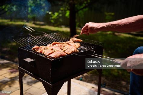 뒤뜰에 있는 바베큐 그릴에서 고기를 요리하는 동안 클로즈업 남성의 손이 포크로 절인 스테이크를 찔렀다 가든파티에 대한 스톡 사진