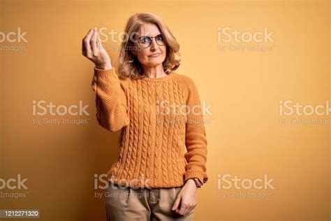 중년 아름다운 금발 의 여자 캐주얼 스웨터와 안경을 입고 노란색 배경 을 하고 이탈리아 제스처 와 손과 손가락 자신감 표정 감정에 대한 스톡 사진 및 기타 이미지 Istock