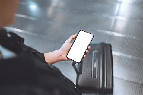 비행기를 기다리는 동안 공항 터미널에서 빈 흰색 화면이 있는 스마트폰을 사용하여 여행 가방을 들고 있는 아시아 남성 여행자의 뒷모습 여행 기술 광고 공간 복사 30 34세에