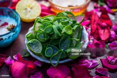 알로에 베라 젤 벌 꿀 우유 크림 레몬의 구성 된 허브 얼굴 팩 닫고 장미와 장미 물과 장미 꽃잎 어두운 고딕 색상에서 나무 표면에 얼굴 팩이 무딘 피부를 제거합니다 0명에