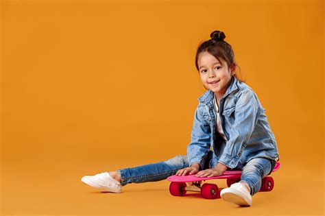 오렌지 배경에 데님에서 스케이트 보드와 세련 된 어린 아이 소녀 아이에 대한 스톡 사진 및 기타 이미지 아이 어린 시절 데님 Istock