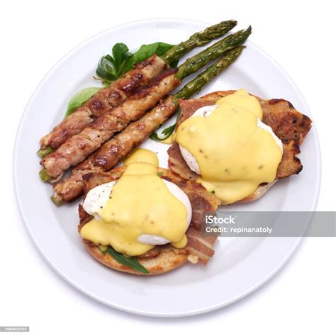 건강 식품 베이컨과 베네딕트 수란으로 감싼 아스파라거스는 흰색 배경에 격리된 접시에 담겨 있습니다 Celebrity Roast에