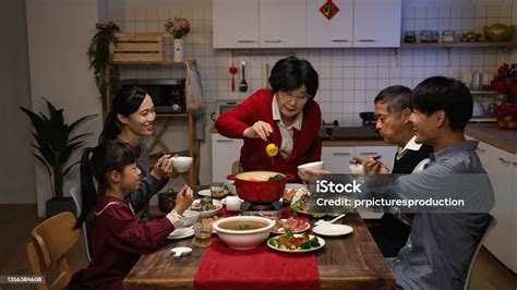집에서 음력 새해 동창회 식사 동안 저녁 식사 테이블에 젓가락을 들고 서 서 있는 가족 할머니의 아시아 수석 여주인 가족에 대한 스톡 사진 및 기타 이미지 Istock