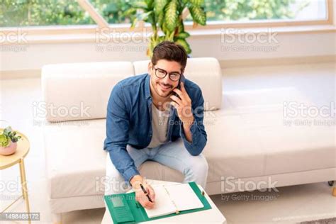 캐주얼 사업가는 집에서 소파에 앉아 전화를 걸고 메모장에 메모를 한다 30 34세에 대한 스톡 사진 및 기타 이미지 30 34세 40 49세 Brand Name