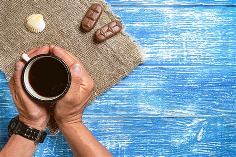 남자는 초콜릿 바와 향기로운 커피 한 잔을 보유 하 고 블루 세 렛 및 바닥에서 오래 된 천으로 디자인 나무 배경 0명에 대한 스톡 사진 및 기타 이미지 Istock