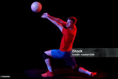 네온 라이트의 어두운 배경에 고립 된 공을 가진 남성 배구 선수 훈련의 역동적 인 초상화 스포츠 체육관 팀 스포츠 도전 과제
