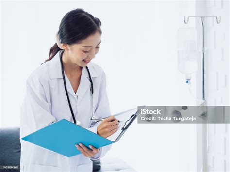 종이 파일을 가진 의사 아시아 여성 의사들은 의료 문서 또는 환자 검사 노트를 클립 보드에 펜으로 씁니다 병원이나 진료소에서 일하는 청진기를 입은 흰 양복을 입은 의사 20