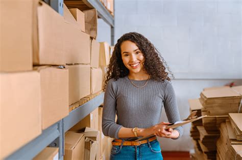 산업 서류 작업이나 골판지 또는 패키지 배달에 종사하는 비즈니스 여성과의 재고 보관 또는 재고 클립 보드 공장 및 관리자가 상자를 포장하는 미소로 창고에서 일합니다 20