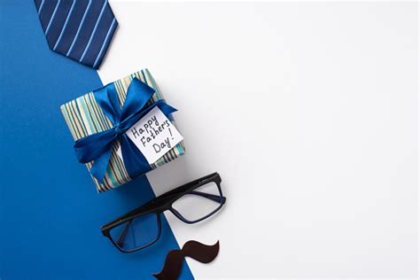 아버지의 날 개념 리본 활과 엽서 파란색 넥타이 안경과 카피 스페이스가있는 이중 색상의 파란색과 흰색 배경에 콧수염이있는 세련된 선물 상자의 탑 뷰 사진 선물에 대한 스톡