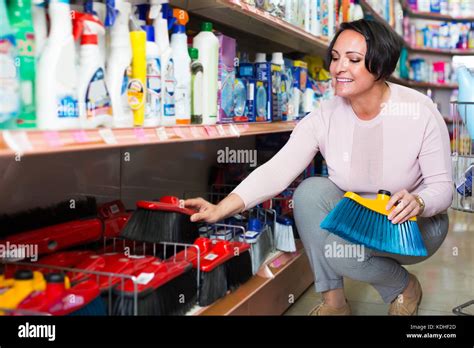 Joyful Smiling Mature Housewife Selecting Cleaning Brush In