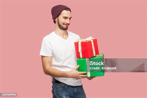 교활하고 웃는 수염을 기른 남자가 선물 상자를 들고 서서 교활한 표정으로 카메라를 바라보고 있습니다 20 24세에 대한 스톡