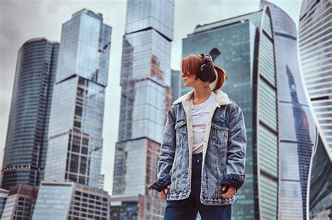 그녀의 얼굴에 문신과 힙 스 터 소녀 옷을 입고 헤드폰은 흐린 아침에 모스크바의 고층 빌딩 앞에서 음악을 듣고 생활 방식에 대한 스톡 사진 및 기타 이미지 Istock