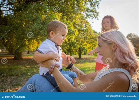 La Madre Juega Con Su Hijo Y Lo Hace Sentarse En Su Regazo La Hija En El Trasfondo De La