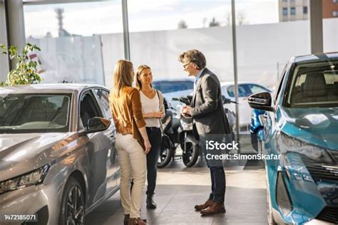 자동차 대리점에서 실내에서 사업가와 대화를 나누는 두 명의 여성 고객 모두 새 차 옆에 서 있습니다 차에 대한 스톡 사진 및 기타 이미지 Istock