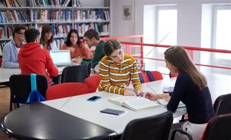 一群学生坐在图书馆里利用现代技术为学校创建一个项目高清摄影大图 千库网