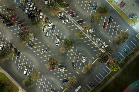 조명 된 주차장에 주차 된 많은 차량의 위에서보기에는 주차 장소 및 방향에 대한 선과 표시가 있습니다 쇼핑몰 센터 앞 차량 배치 경제에 대한 스톡 사진 및 기타 이미지