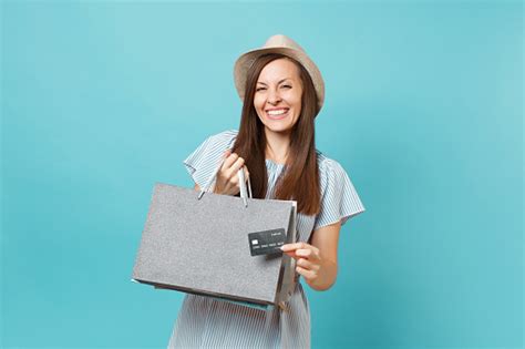 여름 드레스 밀 짚 모자 쇼핑 후 구매와 패키지 가방을 들고 아름 다운 백인 여자의 초상화 은행 신용 카드 블루 파스텔 배경에 고립 광고에 대 한 공간을 복사 합니다 가방에