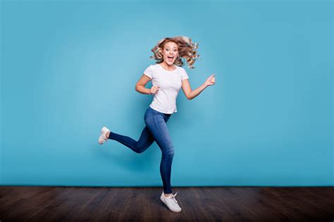 전체 길이 바디 크기 보기 좋은 사랑 스러운 매력적인 여성 쾌활 한 명랑 낙관적 미친 물결 모양의 레이디 캐주얼 흰색 T 셔츠에 빠르게 고립 된 파란색 배경 위에 실행 T