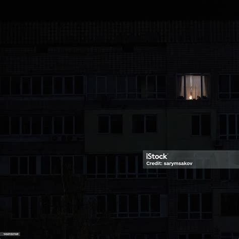 러시아 포격 후 키예프의 주거 지역에서 전기가 정전되는 동안 아파트 다층 건물의 한 창에 불이 들어옵니다 0명에 대한 스톡 사진