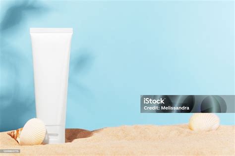 화장품 플라스틱 튜브 영양 또는 보습 크림 마스크 조개와 모래와 해안 배경에 로션을위한 용기 복사 공간이 있는 빈 브랜드 가문