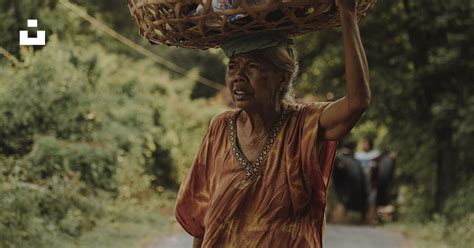 주황색과 파란색 사리 드레스를 입은 여자가 갈색 짠 바구니를 들고 있다 사진 Unsplash의 무료 인도네시아 이미지