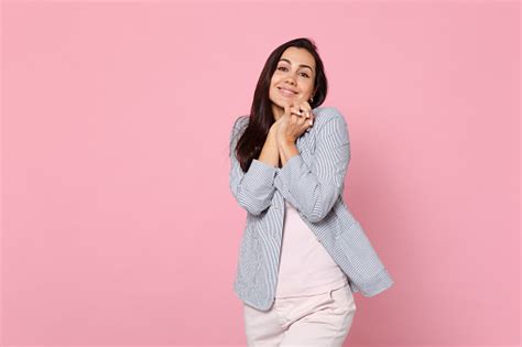 스튜디오에서 분홍색 파스텔 벽 배경에 고립 된 손바닥을 들고 서 있는 줄무늬 재킷에 예쁜 웃는 젊은 여자의 초상화 사람들은 진심으로 감정 라이프 스타일 개념입니다 복사