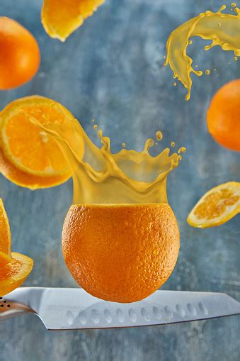 갓 자른 오렌지 부양 칼이 오렌지를 자른다 오렌지는 다른 방향에서 주스와 주스 흐름을 뿌린다 파란색 배경에 오렌지의 비행 조각 감귤류 과일에 대한 스톡 사진 및 기타 이미지