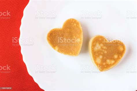 발렌타인 데이를위한 창조적 인 아침 식사 흰색 접시에 하트 모양의 팬케이크 빨간색 배경에 발렌타인 데이 배경입니다 맨 위 보기 플랫 레이 복사 공간 0명에 대한 스톡 사진