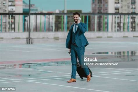 가방을 들고 주차장에 산책 하면서 젊은 관점 웃는 수염 백인 사업가 공식적인 착용 전화 통화 비즈니스 여행 개념입니다 가방에