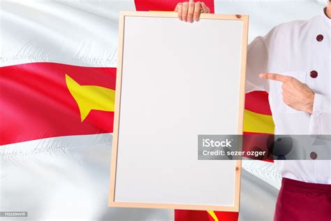 요리사는 건지 국기 배경에 빈 화이트 보드 메뉴를 들고 텍스트에 대 한 균일 한 포인팅 공간을 착용 요리 고급 요리에 대한 스톡 사진 및 기타 이미지 Istock