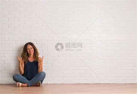 中年的西班牙女人坐在白砖墙上的地板上高喊着疯狂的表情高清图片下载 正版图片505396907 摄图网