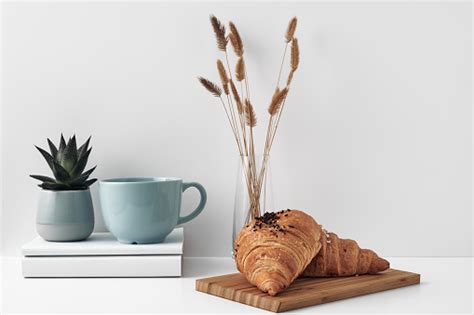 나무 스탠드에 크루아상과 머그잔 꽃병과 책 흰색 배경에 식물이있는 냄비 실내 장식 미니멀리즘의 친환경 소재 공간을 복사하고 모의합니다 0명에 대한 스톡 사진 및 기타 이미지