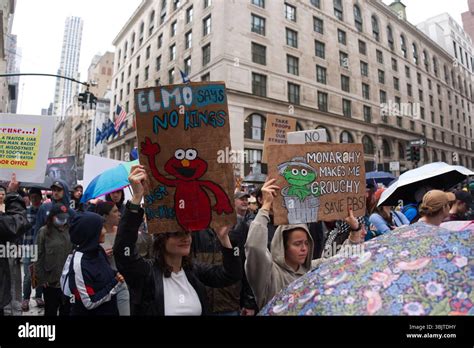 A Protest In A City Setting Features People Holding Signs With Hand