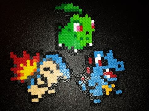 Four Pixel Art Pieces Made Out Of Legos On A Black Surface With One Piece Being Held Up To The Side