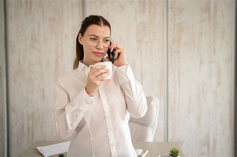 휴대 전화를 사용하여 직장에서 사무실에 서있는 한 여성 사업가 25 29세에 대한 스톡 사진 및 기타 이미지 25 29세 Brand Name Smart Phone