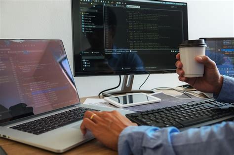 Premium Photo Programmer Drinking Coffee While Using Laptop On Table