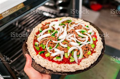 토마토 소스를 곁들인 작은 수제 미조리 피자를 손에 들고 오븐 을 배경으로 다진 간 비건 쇠고기 부스러기로 다진 녹색 피망 양파를 토핑합니다 페이스트리 생지에 대한 스톡