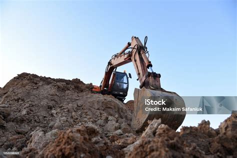일몰 배경에 오픈 피트 광산에서 토공 작업 중 굴삭기 모래 채석장에 양동이가있는 로더 기계 백호 파고 스그라운드 용 기초 및 하수 파이프 를 누워 0명에 대한 스톡 사진 및